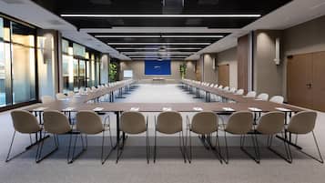 Uma sala de conferência com uma mesa comprida, cadeiras e uma tela de projetor.