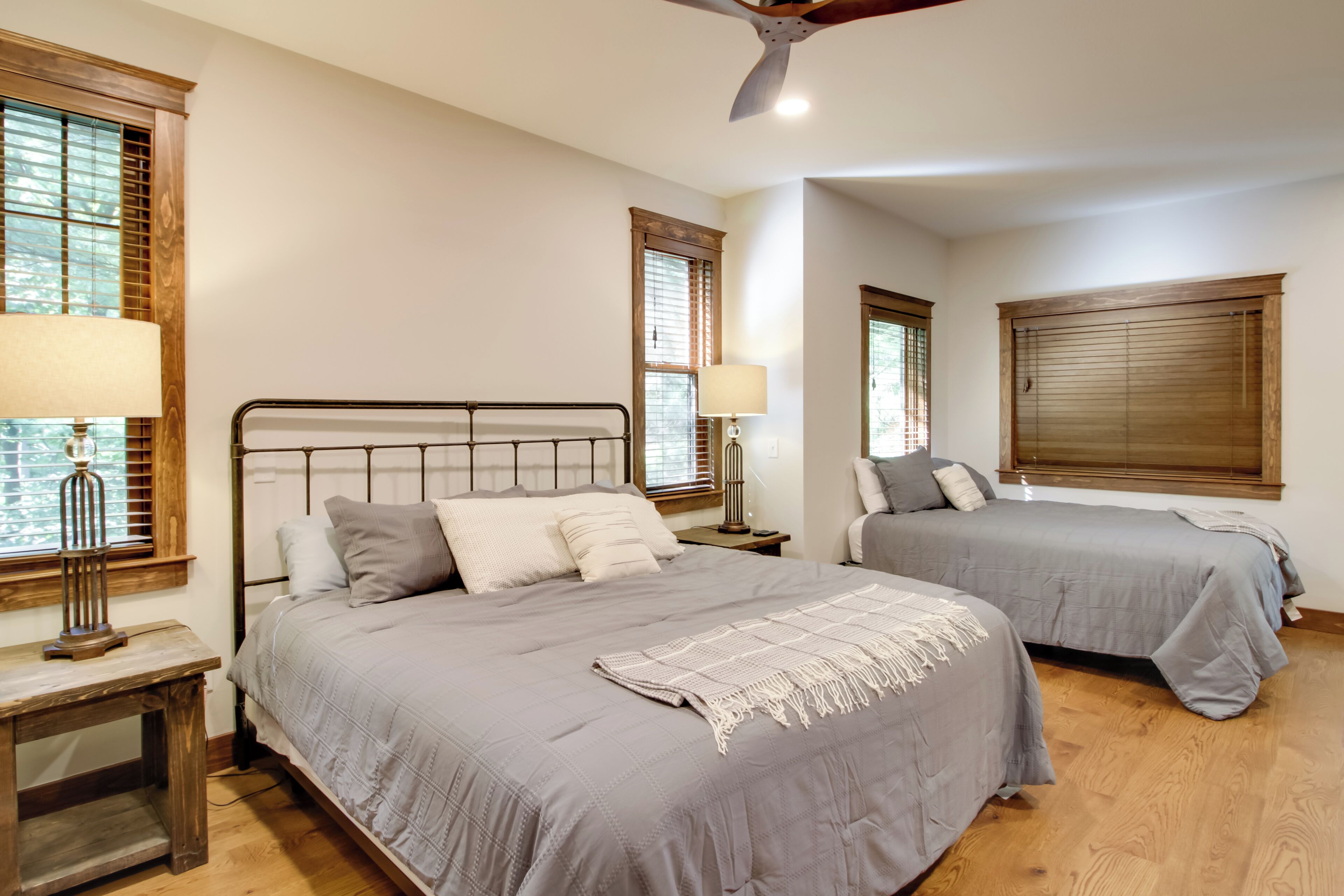 Quarto com duas camas, piso de madeira e ventoinha no teto.