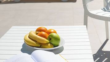 Uma área externa com mesas, um livro e um prato de frutas.