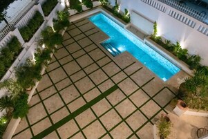 Vista aérea de uma área de piscina com piso em mosaicos e vegetação ao redor.