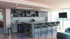 Uma cozinha moderna com bancada de granito, banquetas e prateleiras embutidas.