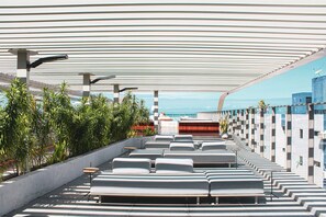 Terraço no telhado com fileiras de assentos, piscina e vista para o oceano.