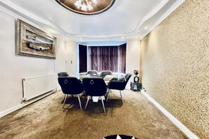 Quarto de hotel com área de jantar, mesa redonda e quatro cadeiras, radiador, uma obra de arte emoldurada na parede e uma parede texturizada.