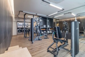 Academia moderna com diversos equipamentos de ginástica, uma máquina de lavar e um saco de pancada.
