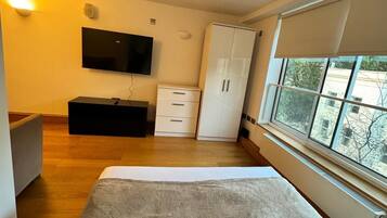 Quarto com cama, televisão, guarda-roupa e janela com vista.