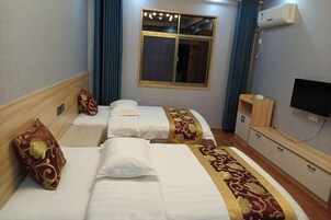 Quarto de hotel com duas camas, televisão, guarda-roupa e janela com cortinas.