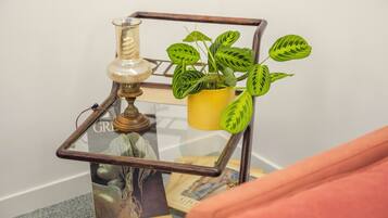 Uma mesinha lateral com tampo de vidro, uma luminária de latão, um vaso com planta e um livro intitulado "GIO".