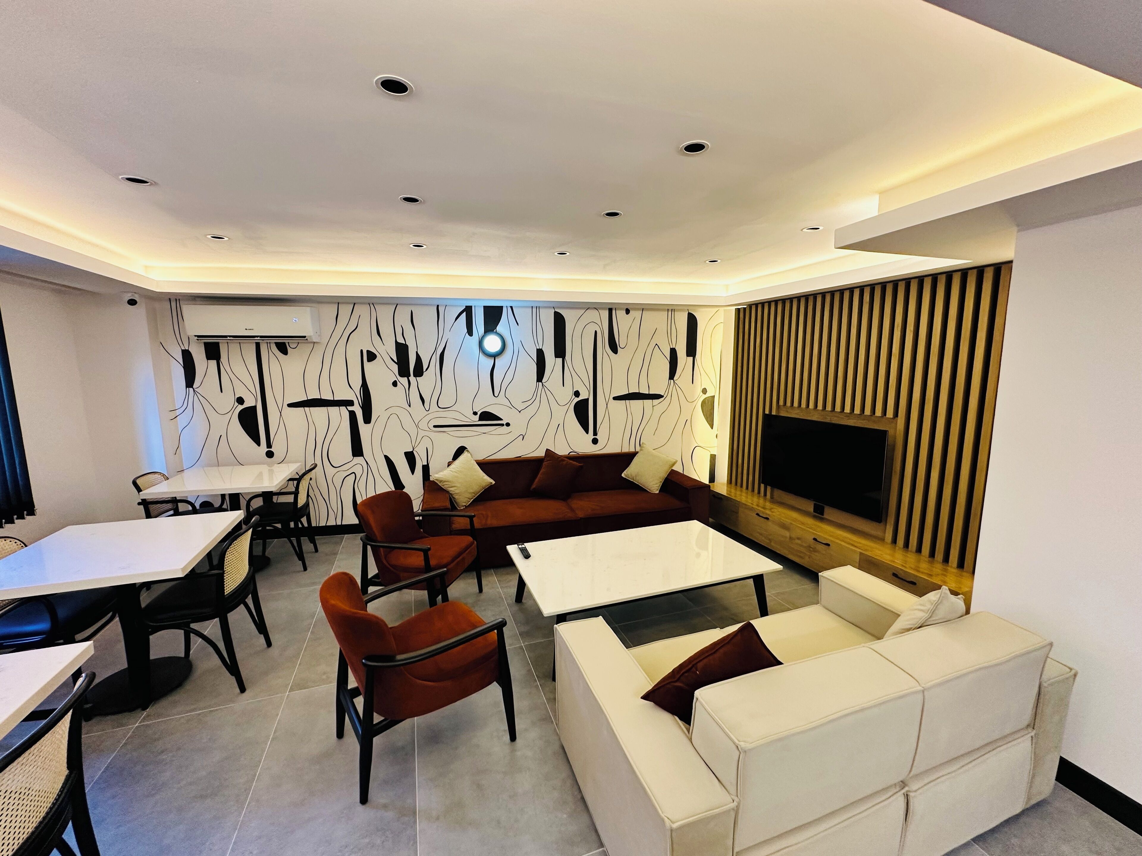 Uma sala de estar moderna com sofá, cadeiras, mesa de centro e televisão.