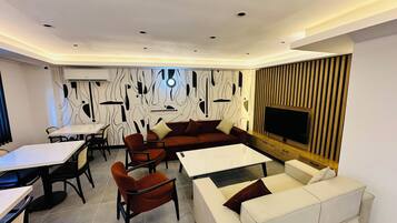 Uma sala de estar moderna com sofá, cadeiras, mesa de centro e televisão.
