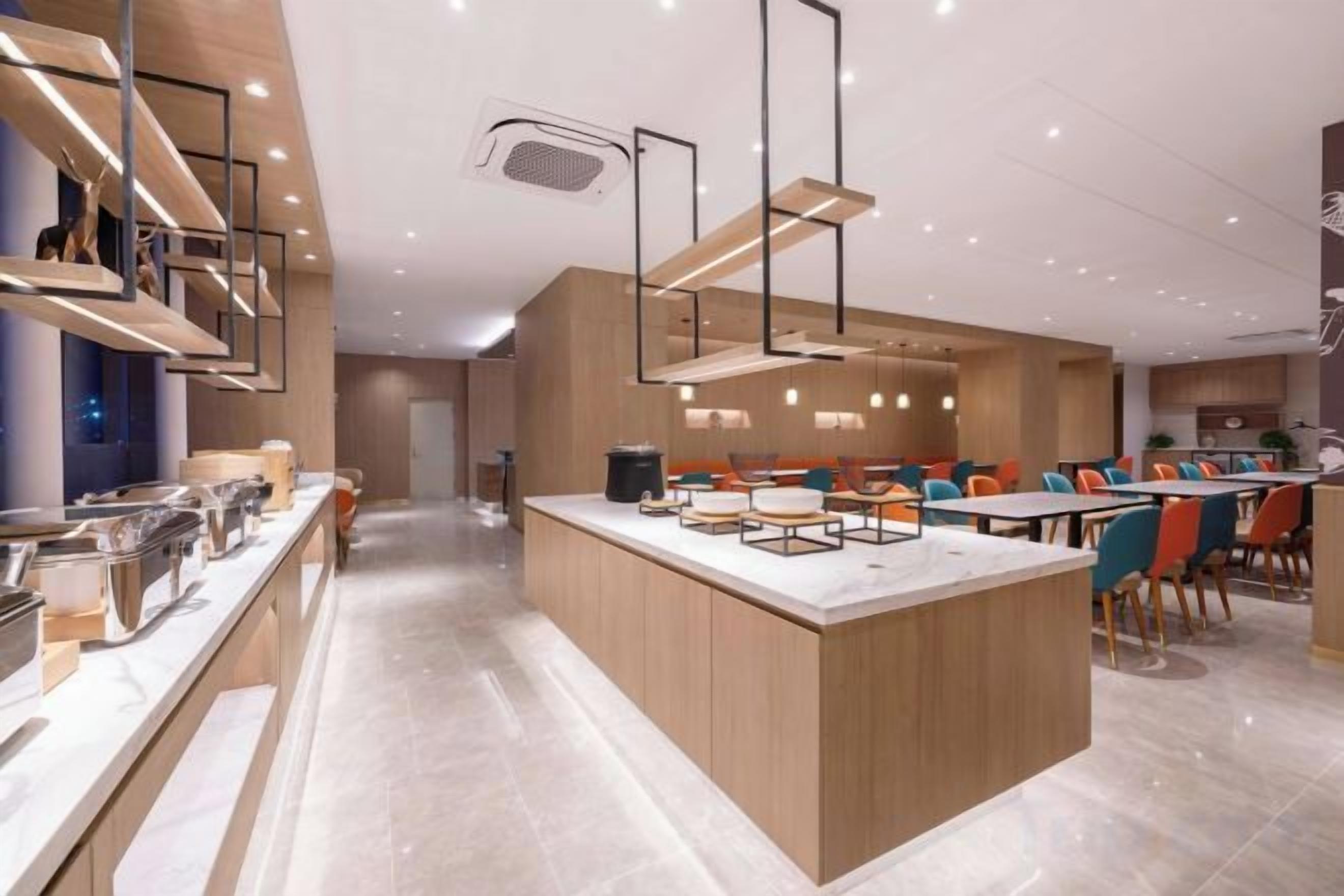 Cozinha moderna com ilha central, iluminação suspensa e área de refeições com cadeiras e mesas.