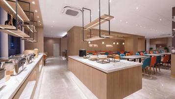 Cozinha moderna com ilha central, iluminação suspensa e área de refeições com cadeiras e mesas.