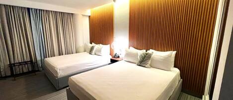 Quarto de hotel com duas camas, parede de madeira e cortina à esquerda.