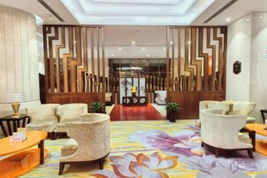 Um lobby com uma recepção central, dois sofás e um tapete estampado.