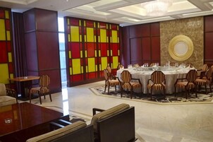 Uma sala de conferência com uma mesa redonda, cadeiras e piso coberto por carpete.
