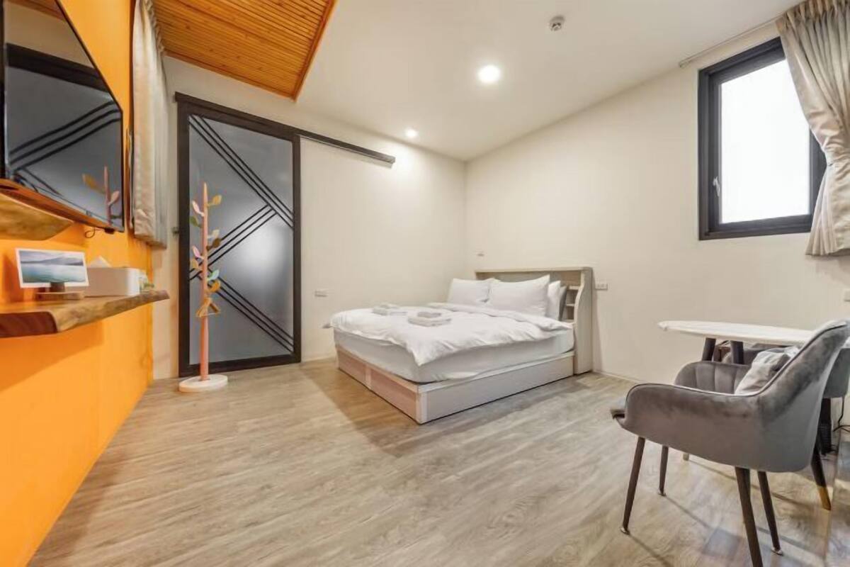 Um quarto com cama, escrivaninha e cadeira.