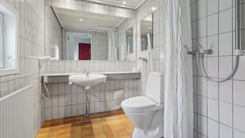 Casa de banho moderna com azulejos brancos, lavatório branco, sanita e chuveiro com cortina.