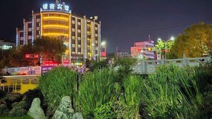 Hotel com fachada curva, vários andares e letreiros iluminados.