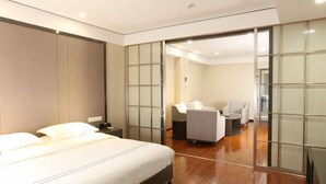 Quarto de hotel moderno com uma cama grande, uma escrivaninha e um espaço de estar.