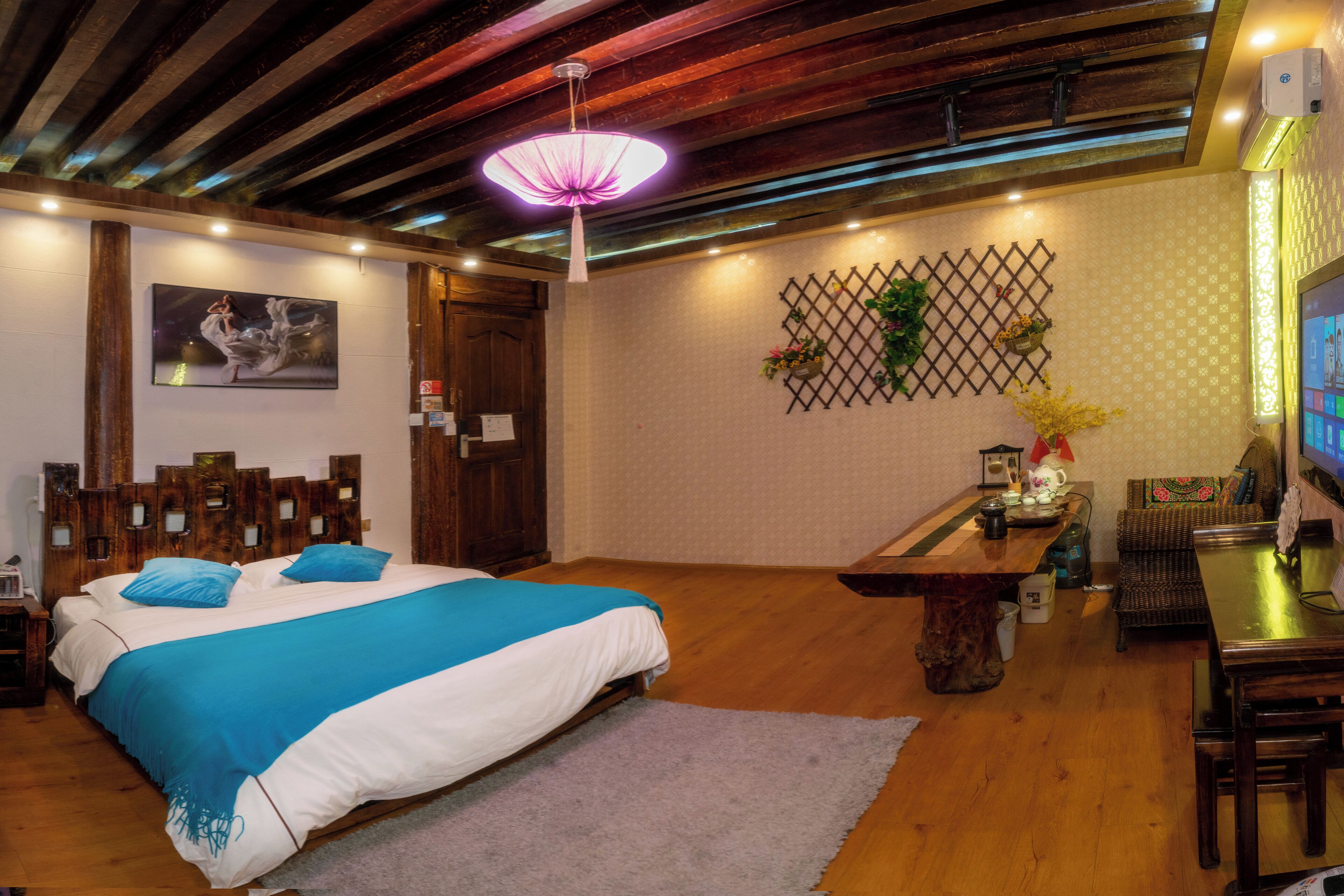 Quarto com cama grande, cabeceira de madeira e teto com vigas aparentes.