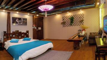 Quarto com cama grande, cabeceira de madeira e teto com vigas aparentes.