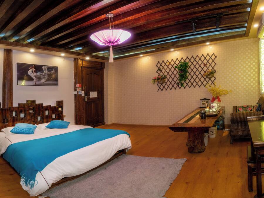 Quarto com cama grande, cabeceira de madeira e teto com vigas aparentes.