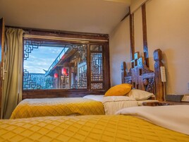 Quarto de hotel com duas camas, cabeceira de madeira e janela com design tradicional em treliça chinesa.