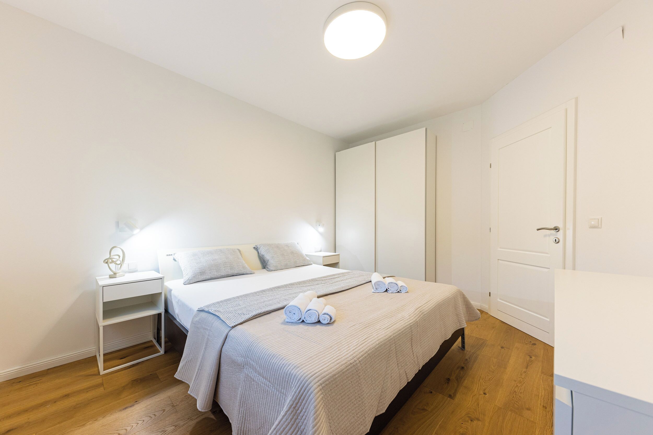 Quarto com cama, mesa de cabeceira e guarda-roupa.