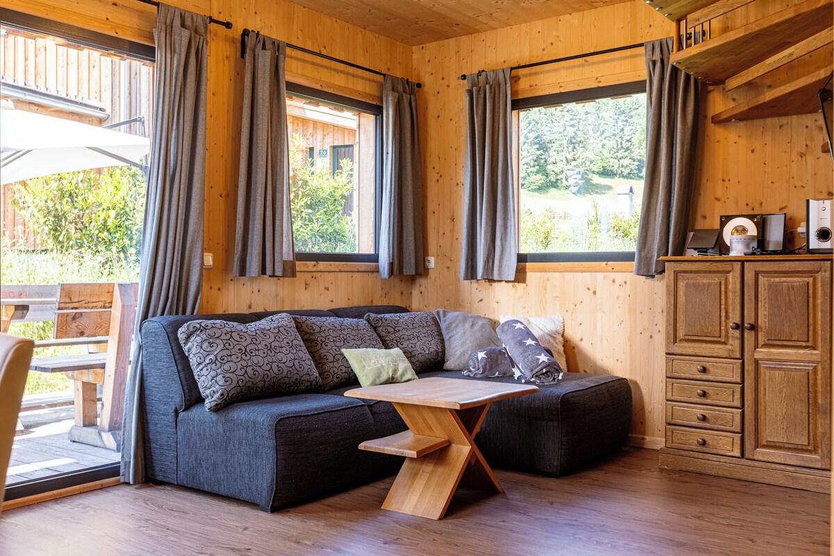 Interior acolhedor de uma cabana com um sofá de madeira, uma mesa pequena de madeira e um armário.