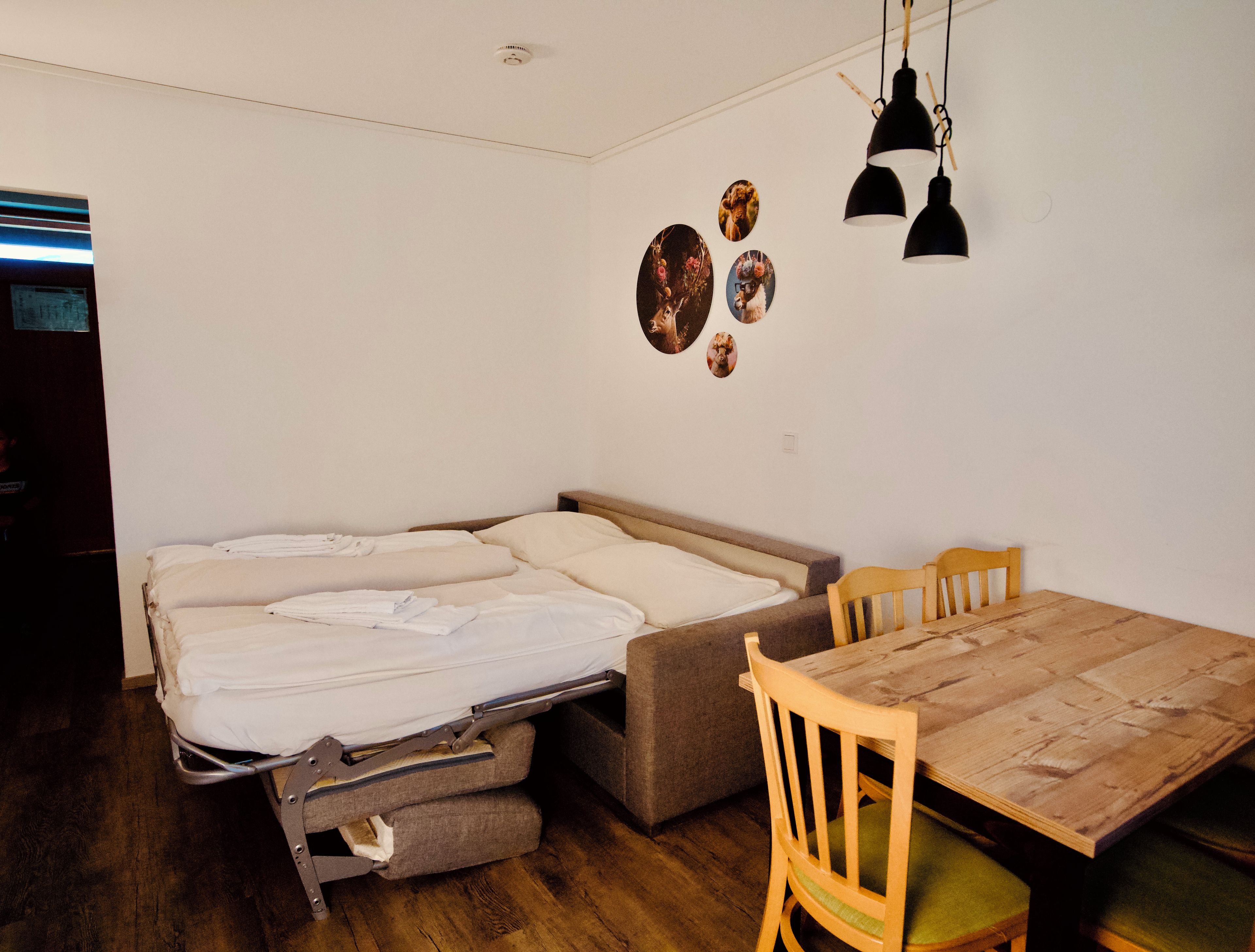 Quarto pequeno com uma cama, uma mesa de jantar e uma cadeira.