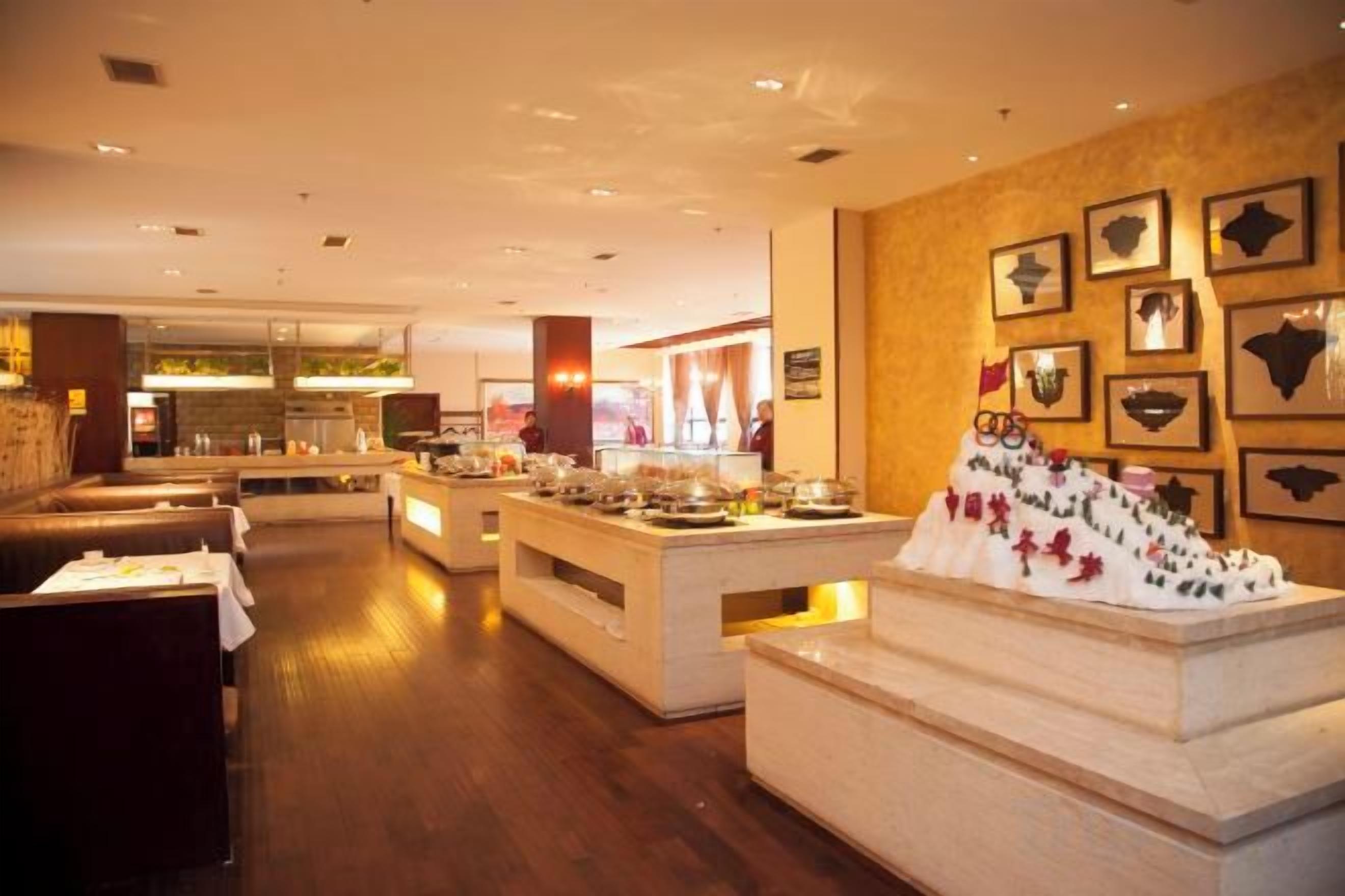 Restaurante com piso de madeira, ilha central com bancada branca e quadros nas paredes.