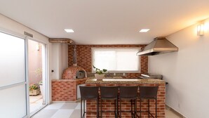 Uma cozinha compacta com painel de ladrilhos, forno embutido e janela.