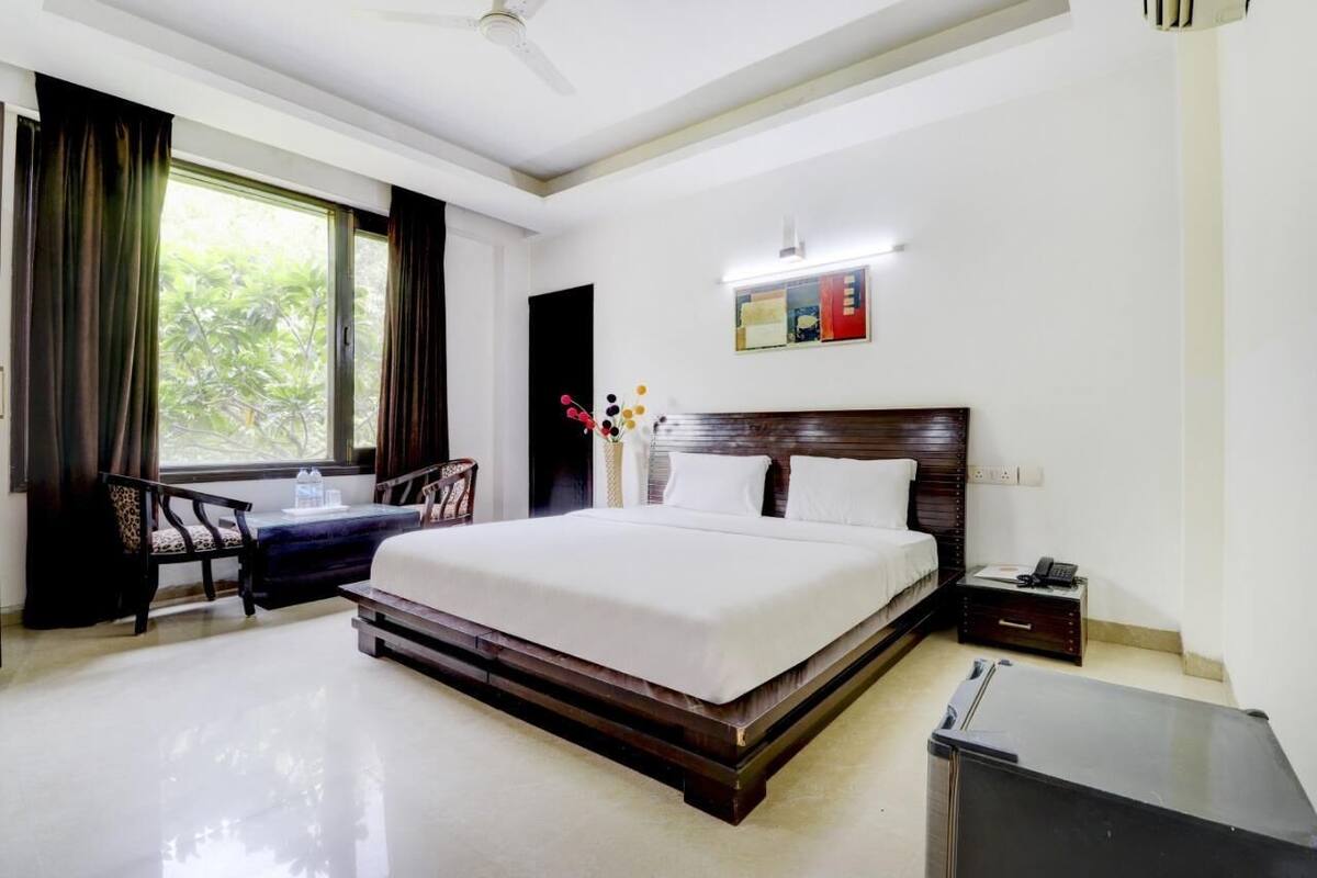 Quarto de hotel com uma cama grande, uma escrivaninha, uma cadeira, uma mesinha e um ventilador de teto.