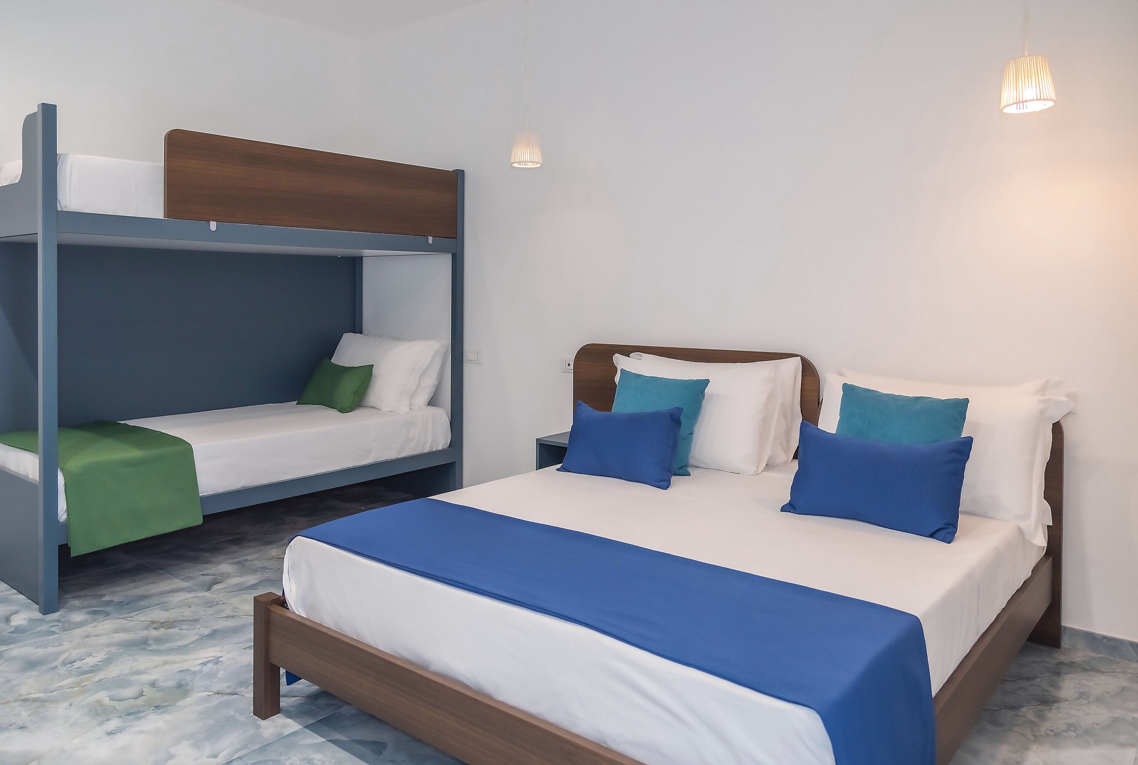 Quarto com uma cama de solteiro, uma beliche e uma mesa de cabeceira.