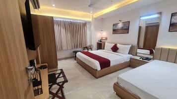 Quarto de hotel moderno com uma cama grande, uma cama menor, uma escrivaninha, uma cadeira e uma televisão.