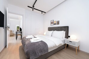 Quarto moderno com cama, mesa de cabeceira e escrivaninha com cadeira.
