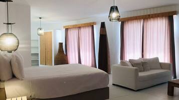 Um quarto moderno com uma cama grande, um sofá branco e um guarda-roupa de madeira.