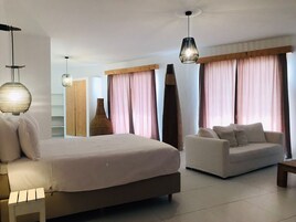 Um quarto moderno com uma cama grande, um sofá branco e um guarda-roupa de madeira.