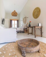 Quarto de hotel moderno com cama, escrivaninha, luminária pendente e vista para a cidade.