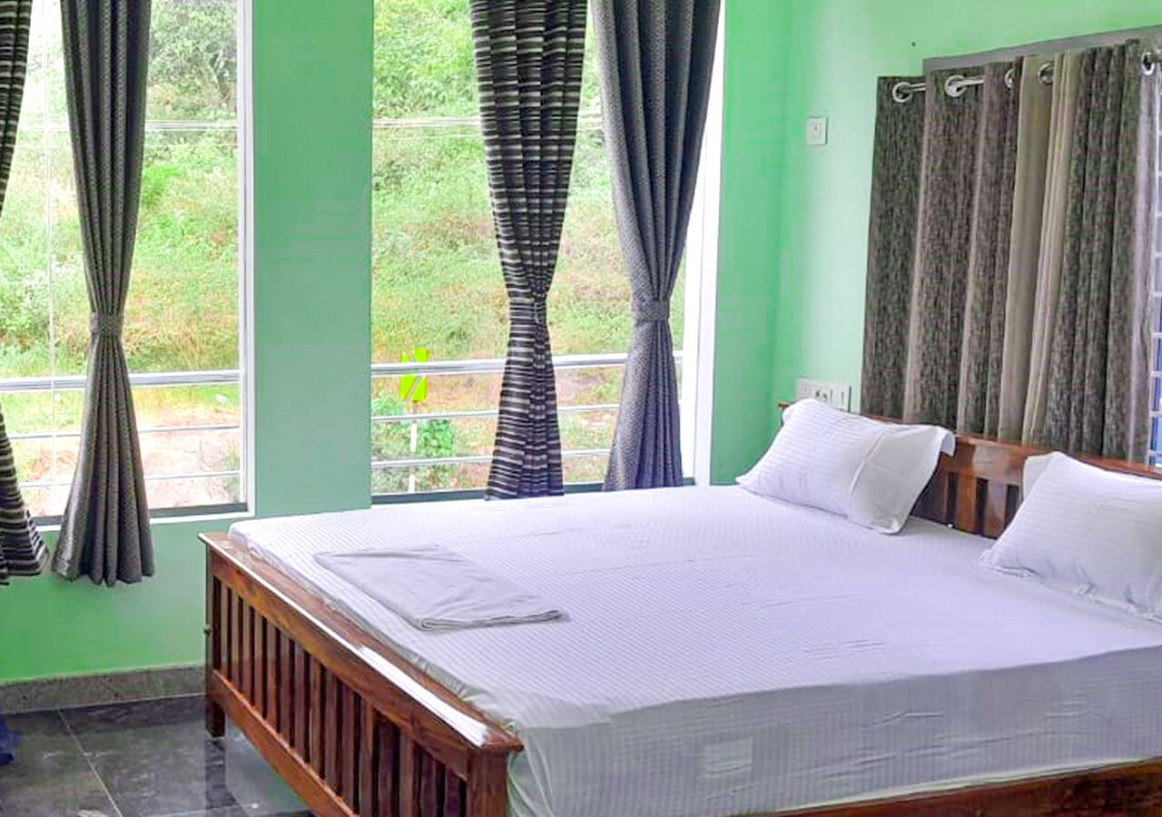Quarto com cama grande, paredes verdes e cortinas.