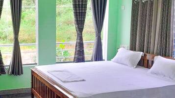 Quarto com cama grande, paredes verdes e cortinas.