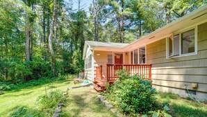 Uma casa térrea com varanda, rodeada por área arborizada.