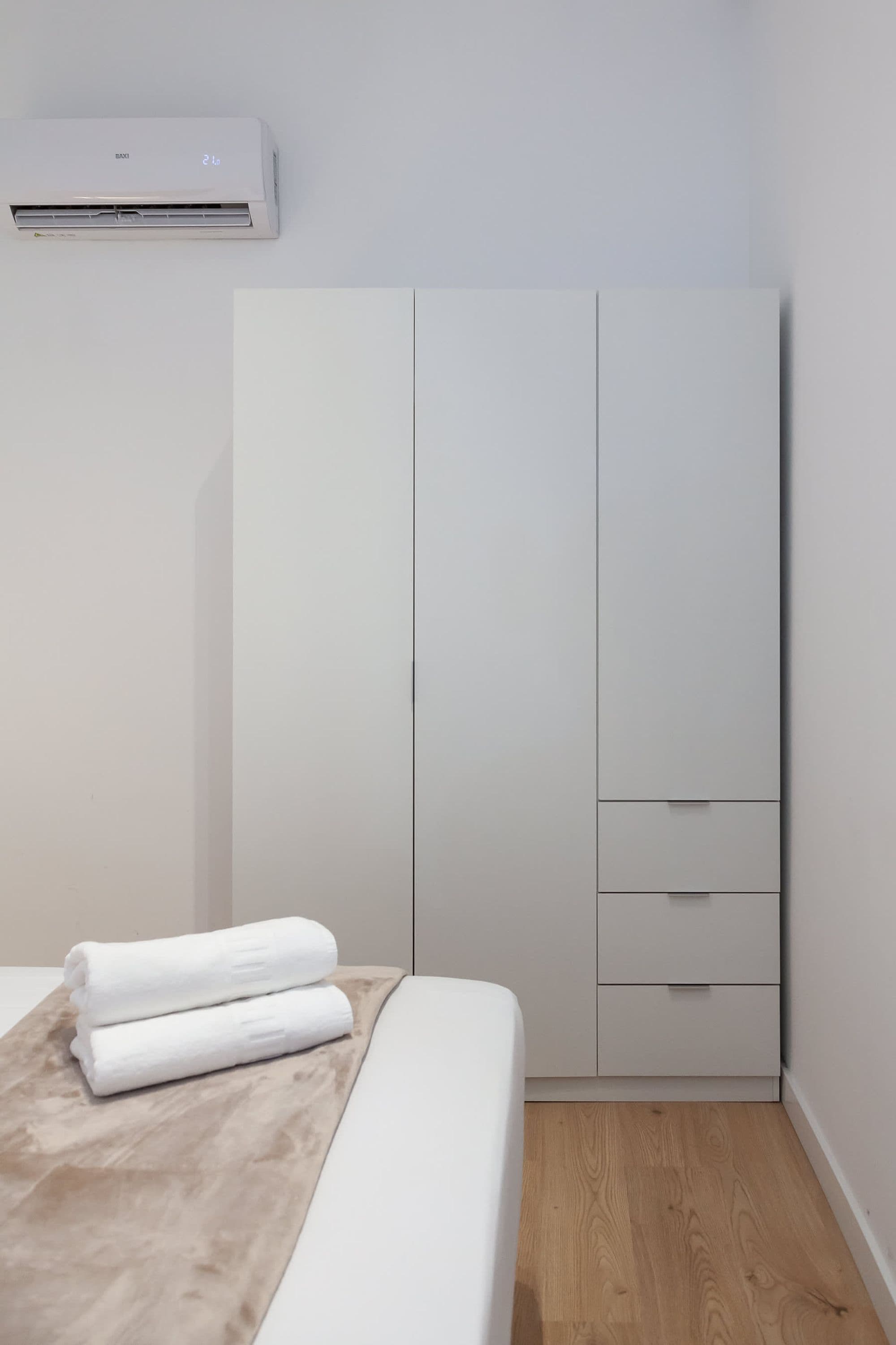 Um quarto com uma cama, um guarda-roupa e um aparelho de ar condicionado.