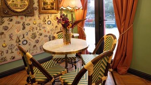 Uma sala de jantar com mesa redonda, cadeiras, um vaso com flores e decorações nas paredes.