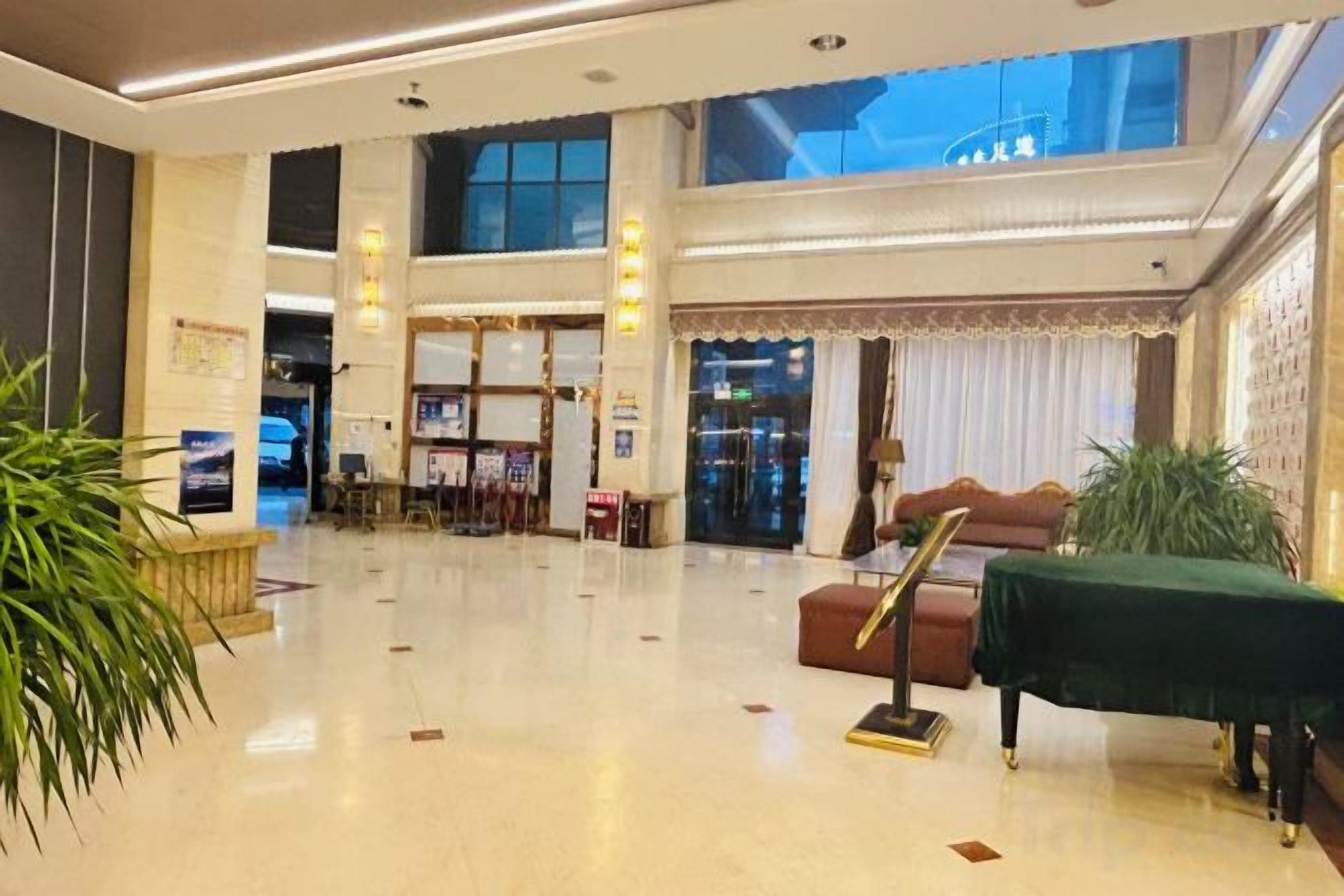 Um hall amplo com balcão de recepção, área de estar e escadaria para os andares superiores.