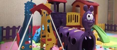 Espaço de recreação infantil com um trem, escorregadores e estruturas de escalada.