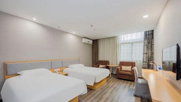 Quarto de hotel com duas camas, uma mesa, uma cadeira e uma televisão.
