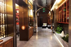 Um corredor com design de interiores moderno, apresentando um lustre central, um espaço de estar e um arranjo de plantas decorativas.