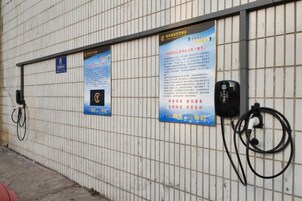 Parede com placa de estacionamento, quadro de avisos e telefone público.