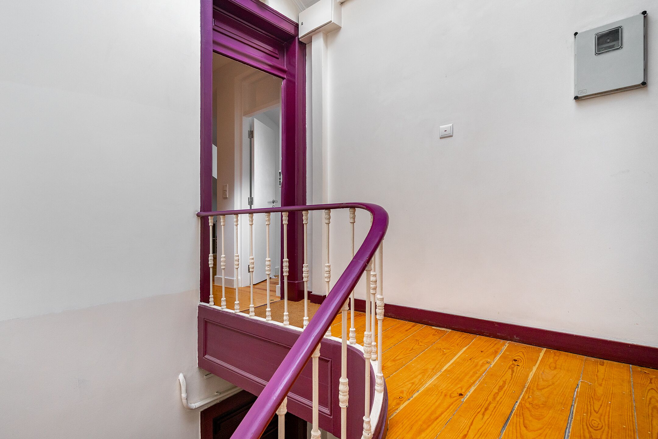 Uma escada com corrimão roxo que leva a uma porta com moldura roxa.