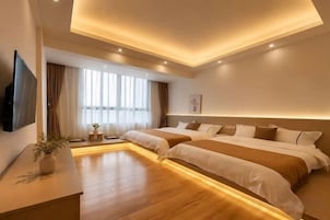 Quarto de hotel com duas camas, televisão de tela plana, mesa de cabeceira e uma janela grande com cortinas.